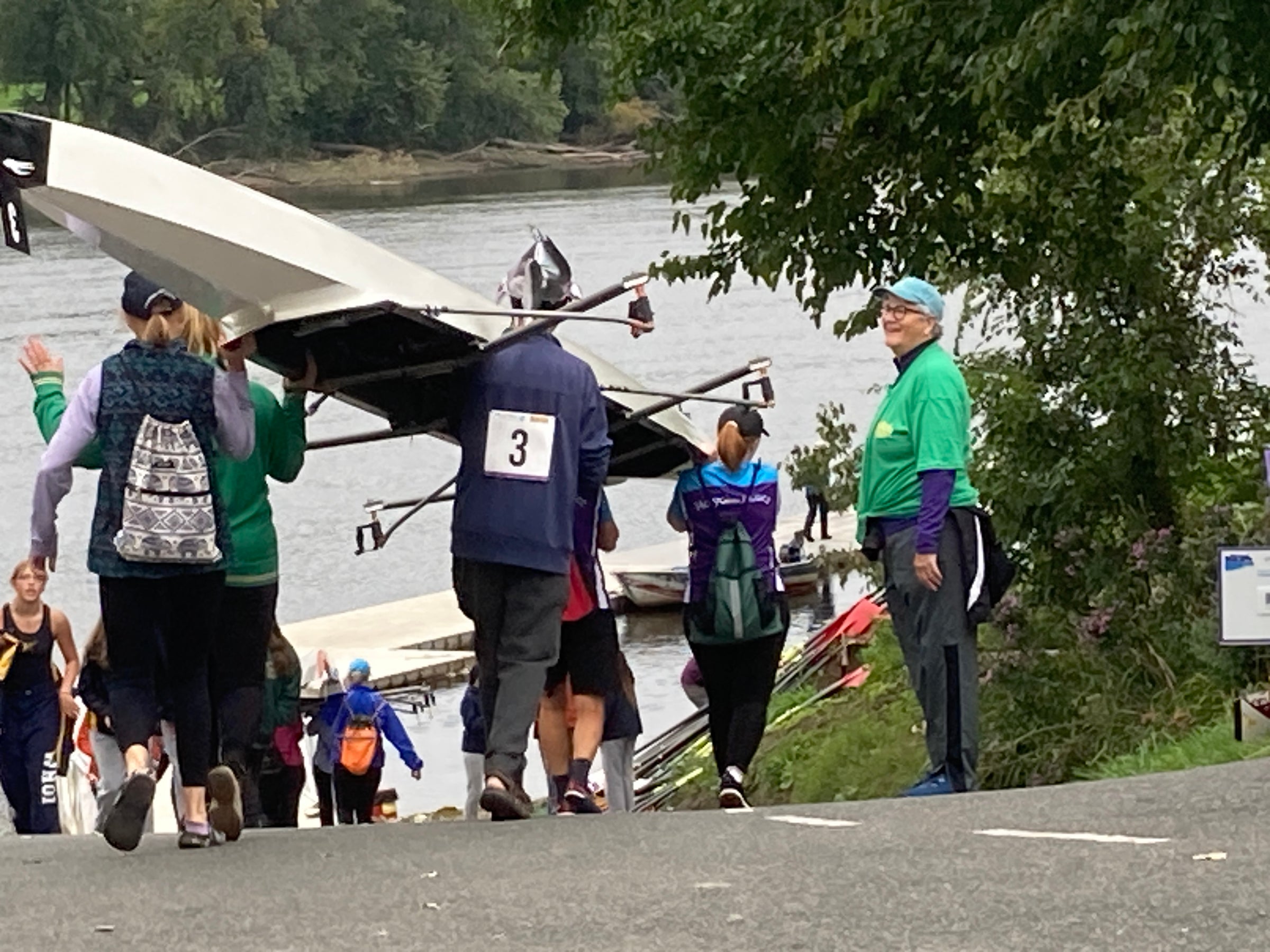 a person in a green Holyoke Rows staff shirt smiles as people carry a ...
