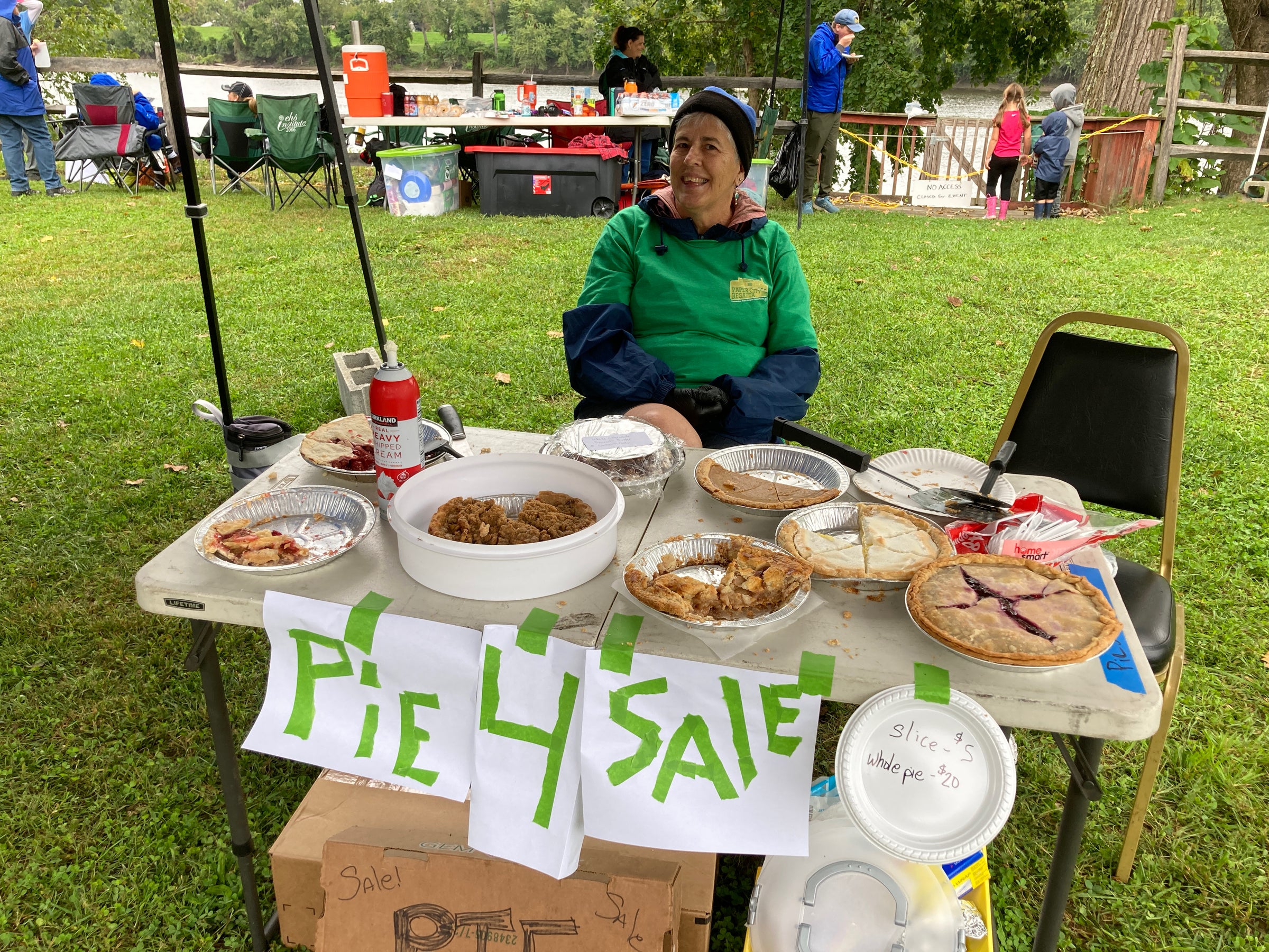 A person in a green Holyoke Rows shirt smiles from behind the pie table ...