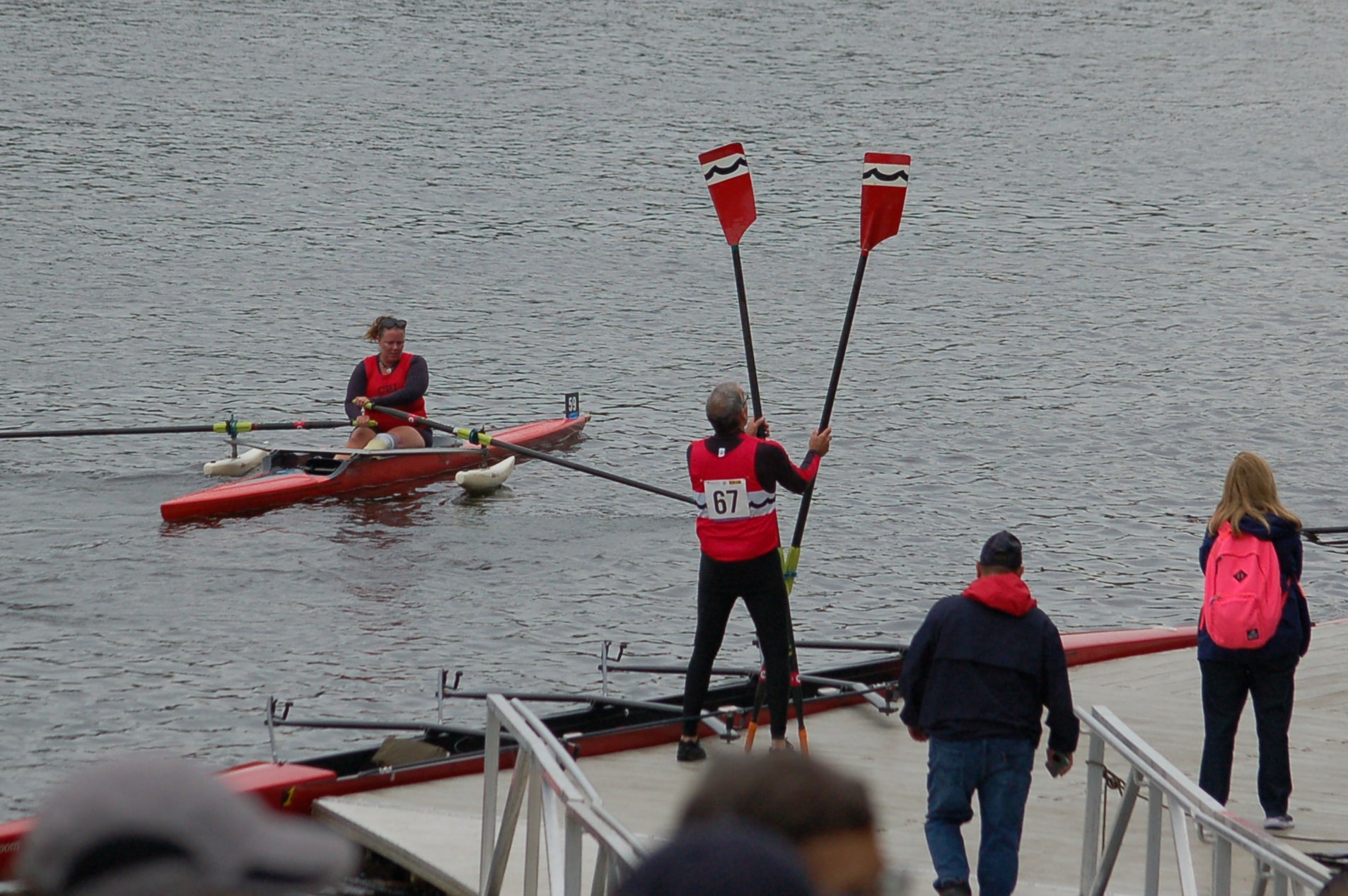On the water, a person in a red jersey rows downstream while a person ...